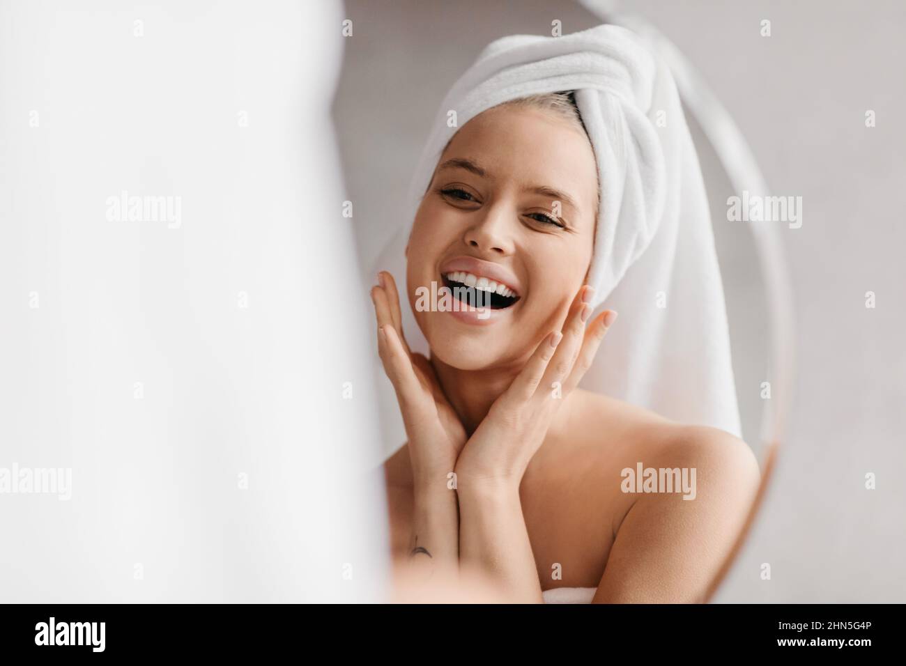 Excited young lady touching her face while looking at mirror in ...