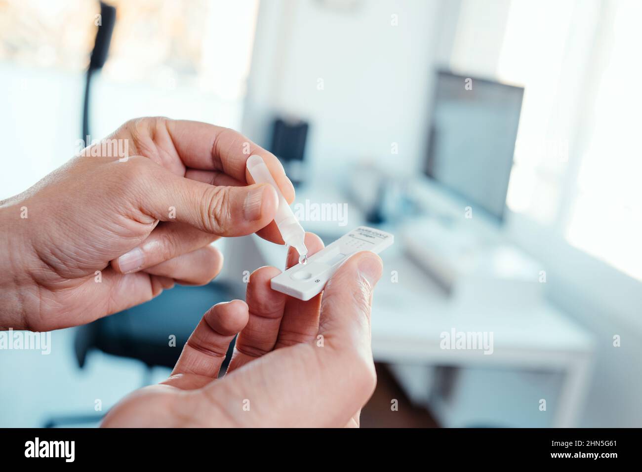 closeup of a young man placing his own sample into the covid-19 antigen ...