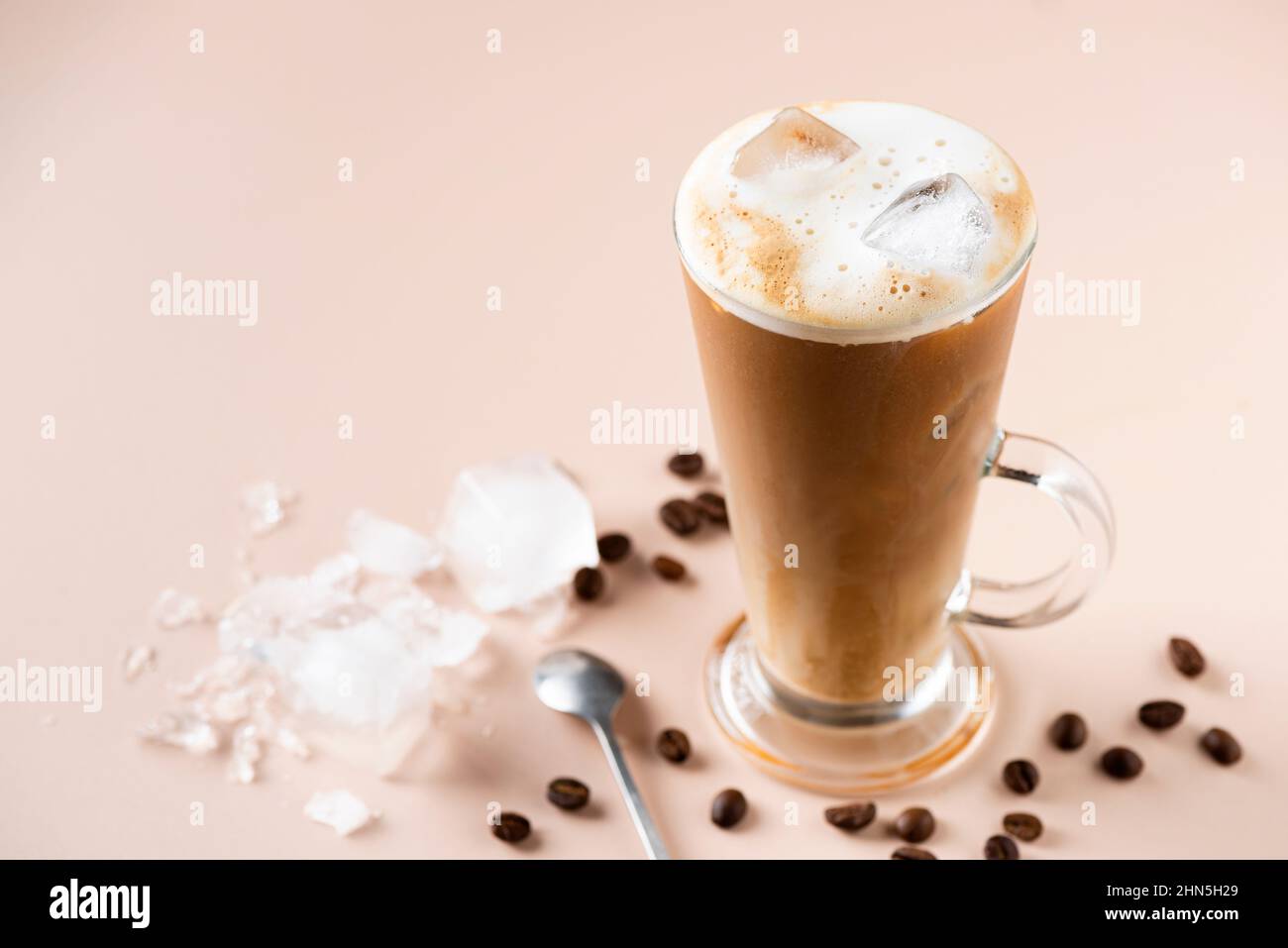 Ice coffee latte in a glass on beige background. Refreshing cold drink ...