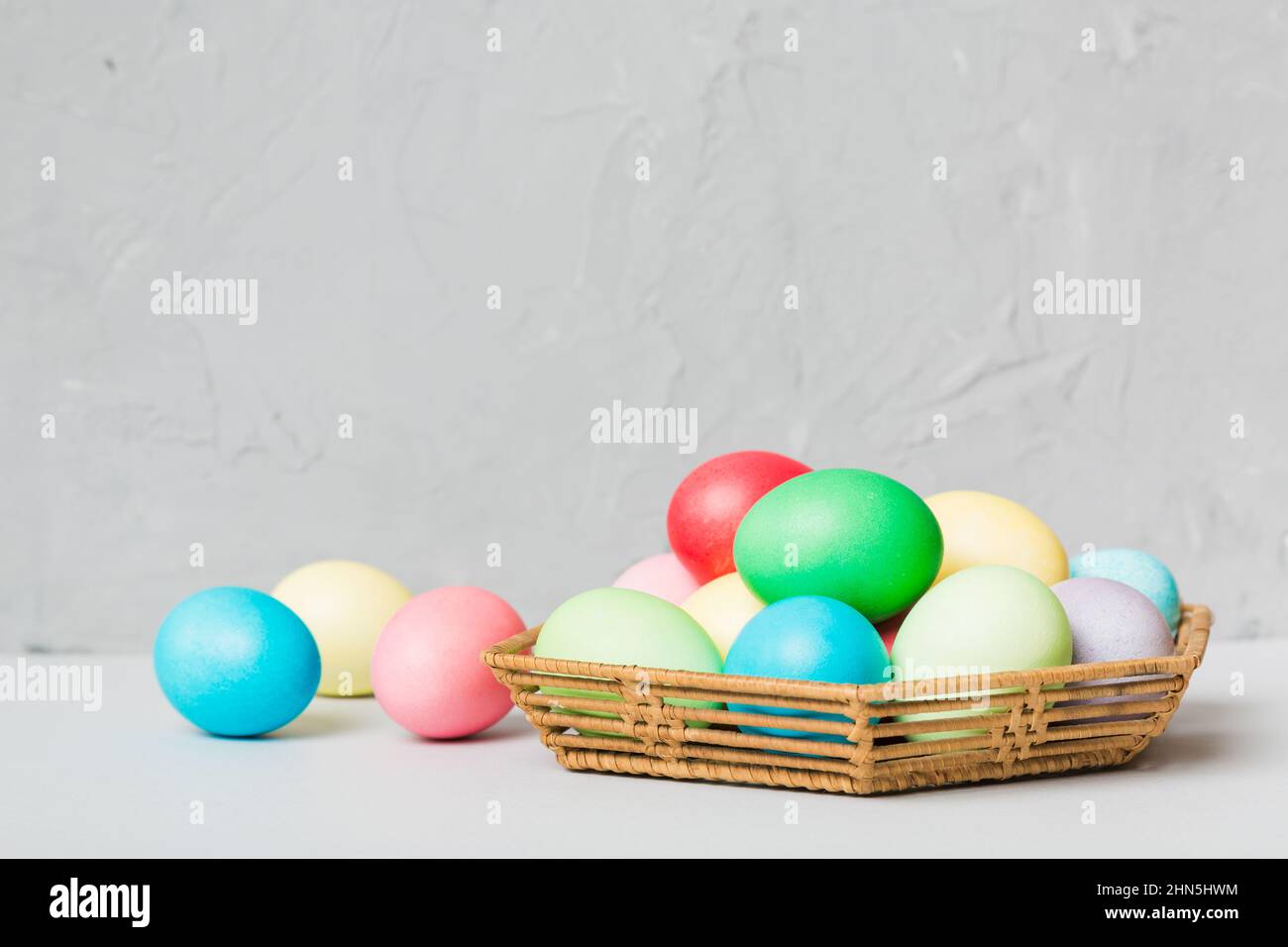 Multi colors Easter eggs in the woven basket on colored background ...