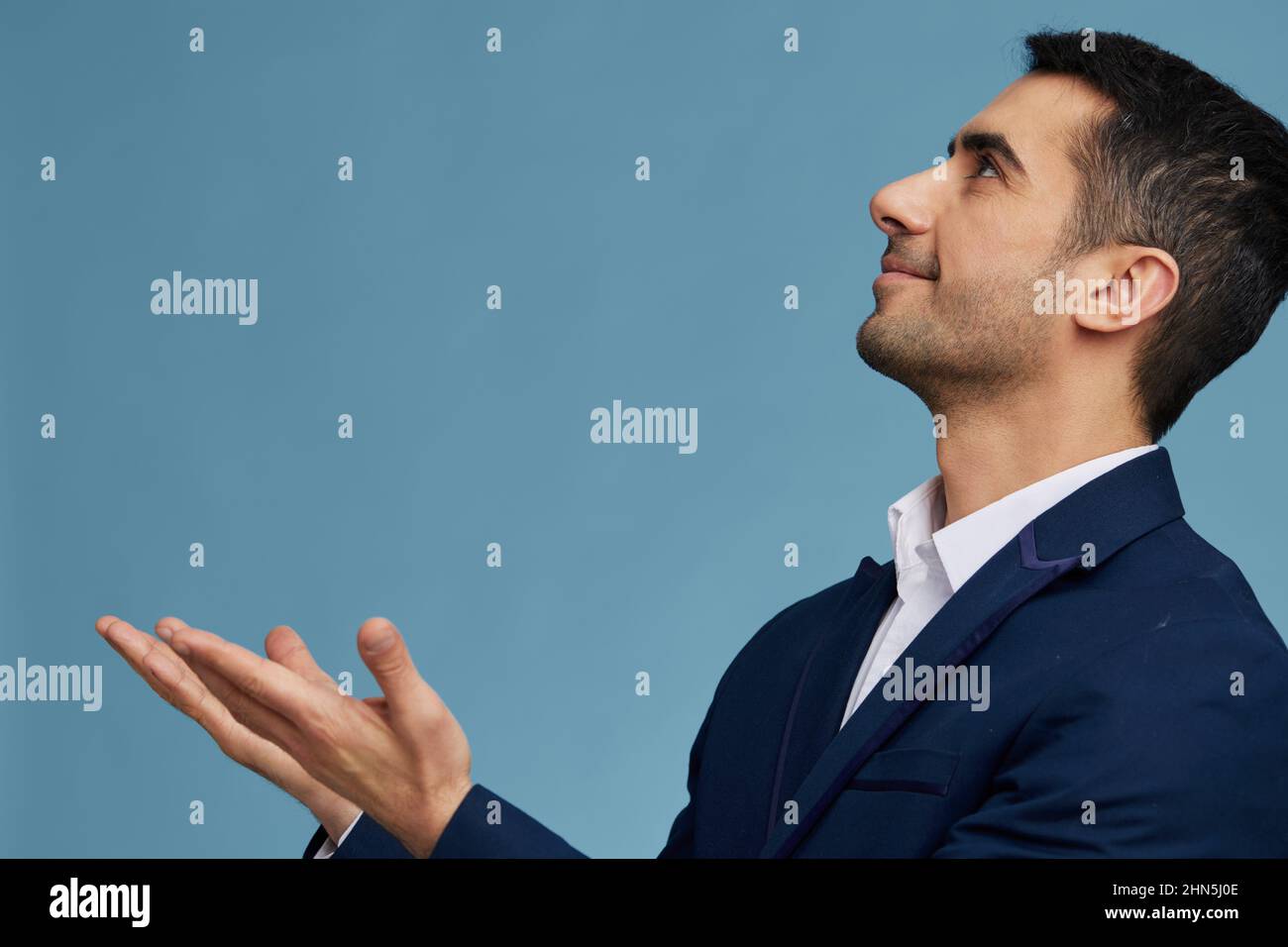 business man in a jacket throws up his hands on a blue background side ...
