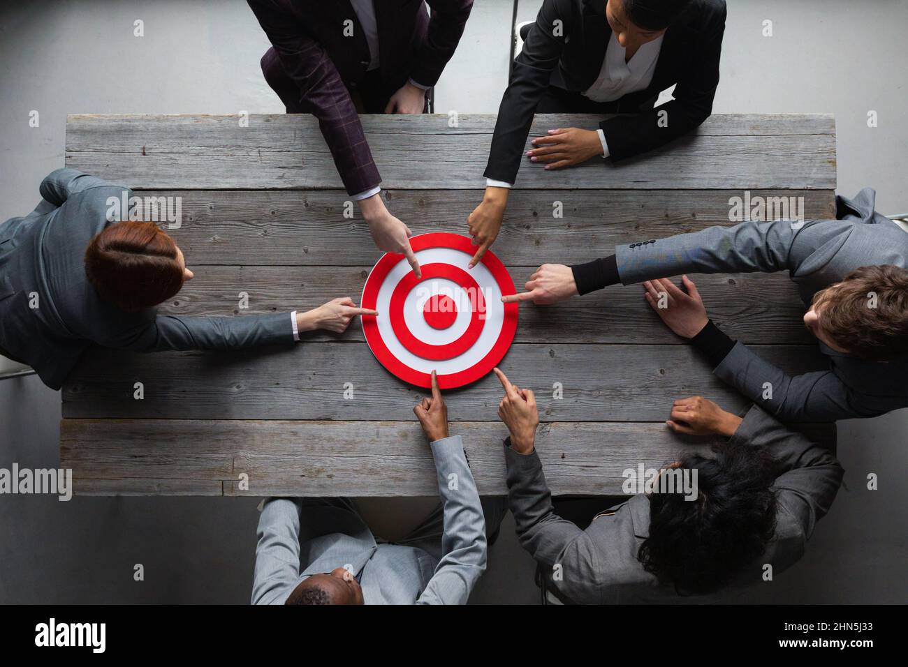 Team of business people pointing at red target at meeting table Stock ...