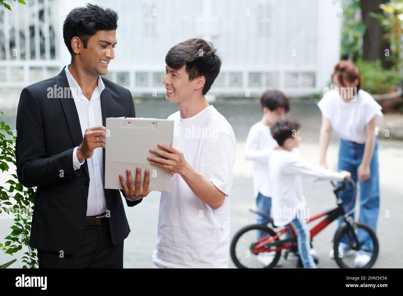 Smiling life insurance agent explaining client how to fill policy for ...