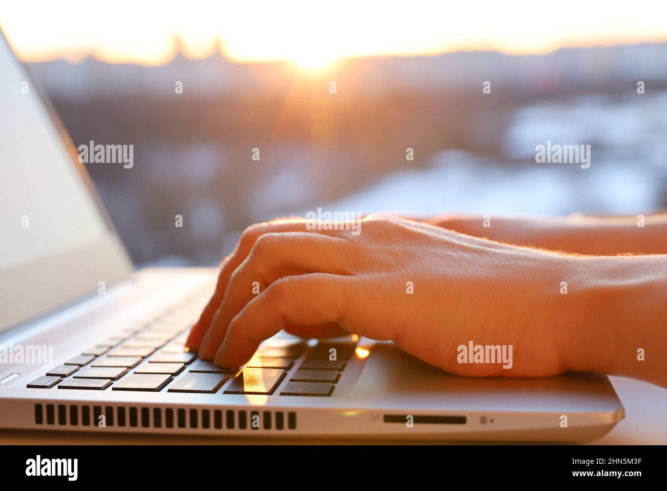 Female hands on laptop keyboard near the window with sunshine. Cozy ...