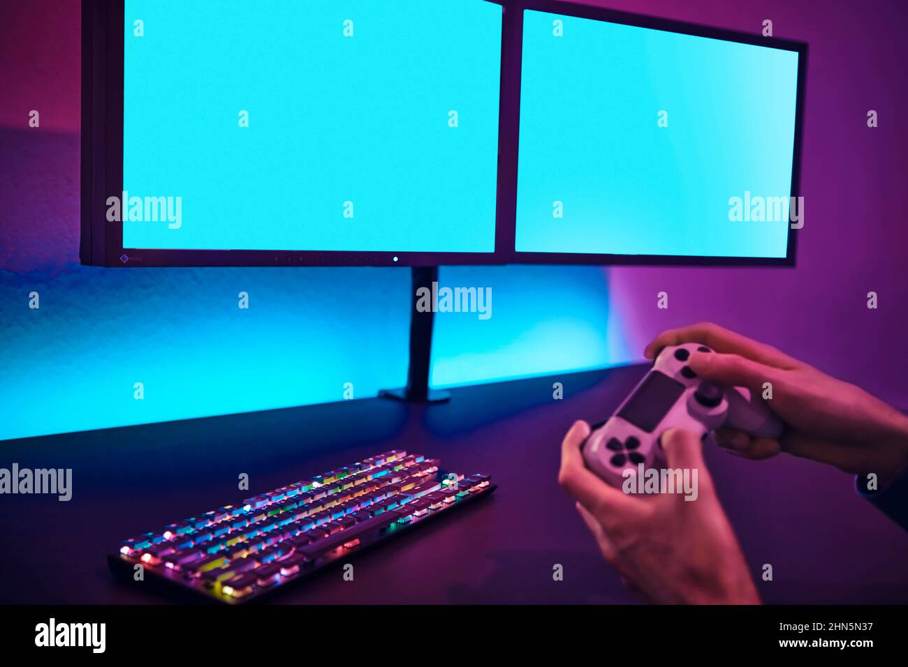 Hands holding game controller. Dual display and cyan / purple ...