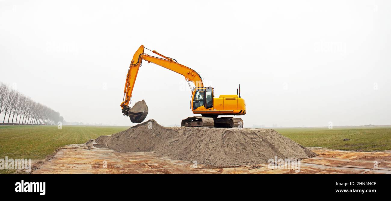 Excavator on a pile of sand Stock Photo - Alamy