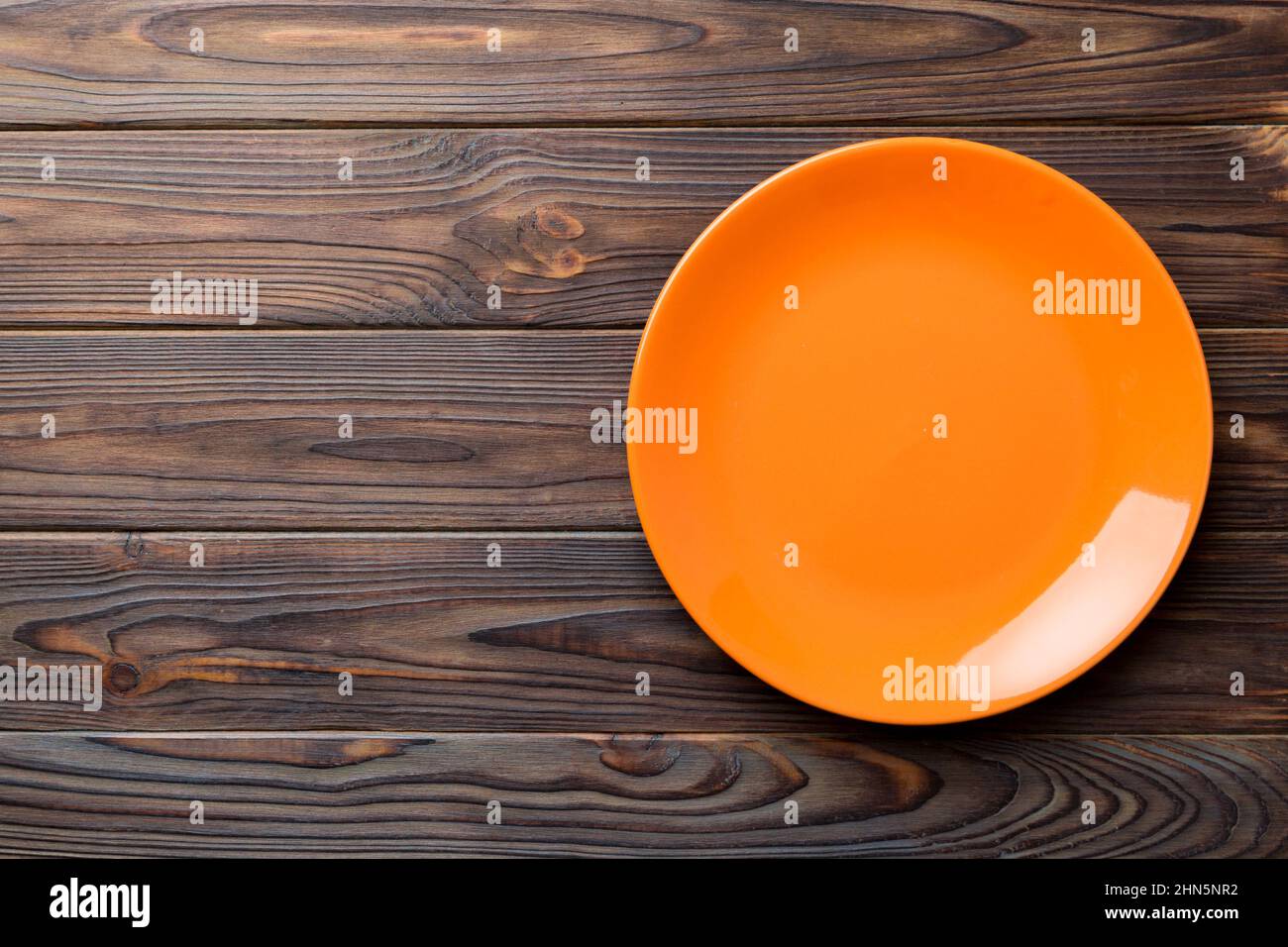 Top view of empty orange plate on wooden background. Empty space for ...