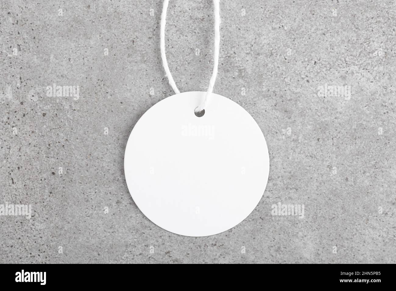 Round white tag mockup with white cord, close up. Blank paper price tag ...