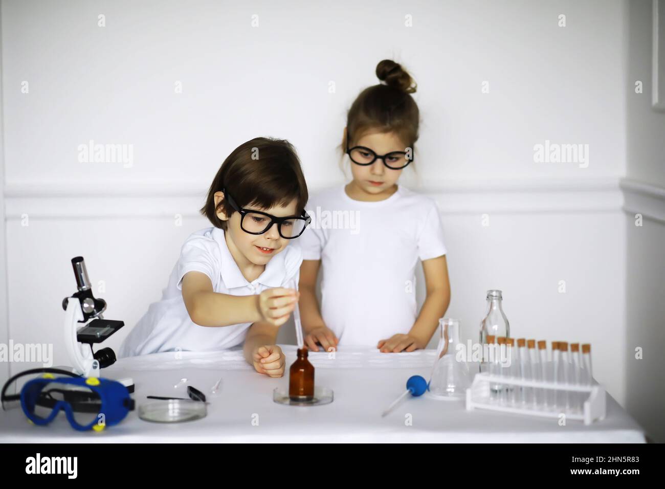 Two cute children at chemistry lesson making experiments isolated on ...
