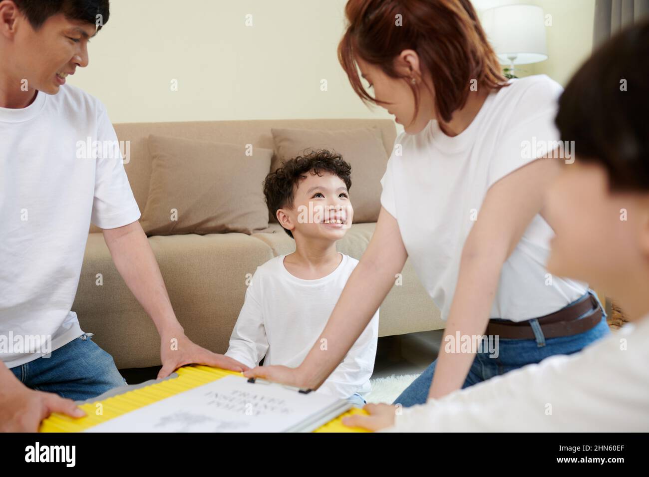 Cheerful little boy helping parents with packing suitcase for vacation Stock Photo - Alamy