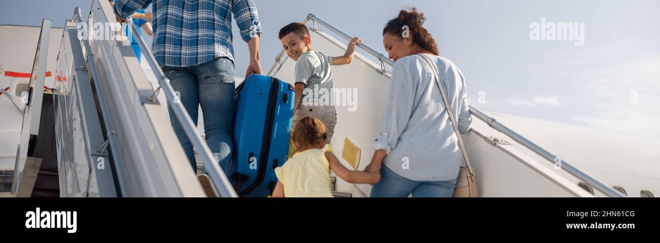 Back view of parents with two kids getting on, boarding the plane on a ...