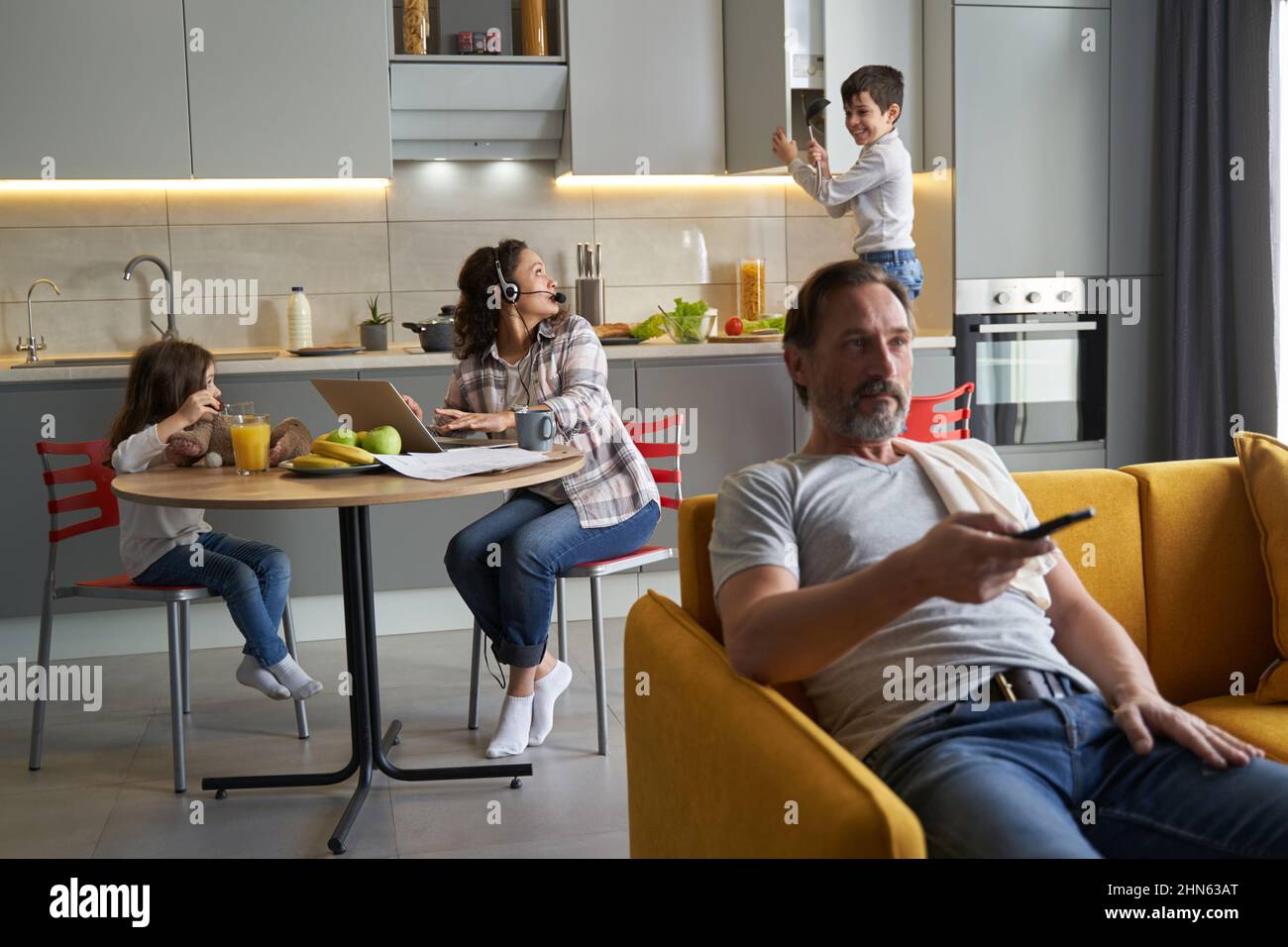 Father watching TV while mother working in kitchen near kids Stock ...