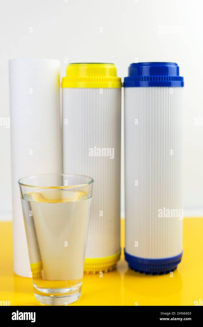 A glass of clean water next to the water purification filter. The ...