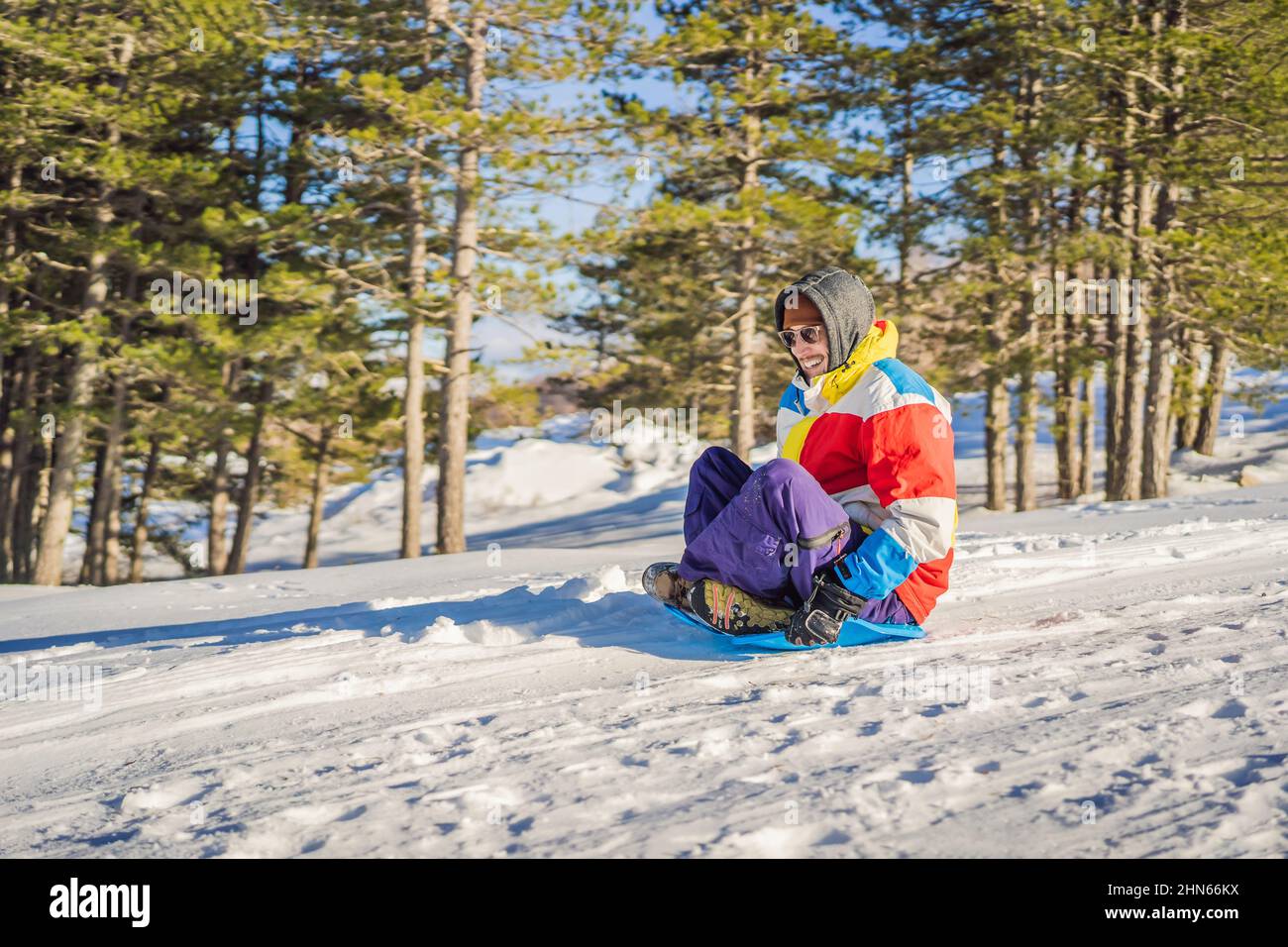 Cheerful man sledding down a snowy slope in full speed Stock Photo - Alamy