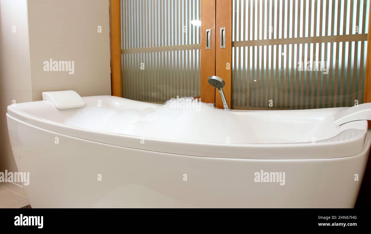 Bathtub with soap suds. Preparing a bath, hot water flows from the tap ...