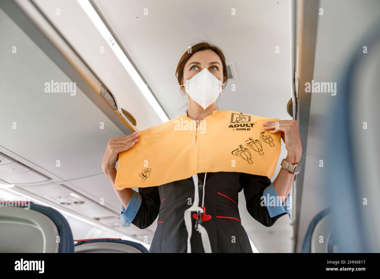 Flight attendant demonstrating how to use life vest in airplane Stock ...