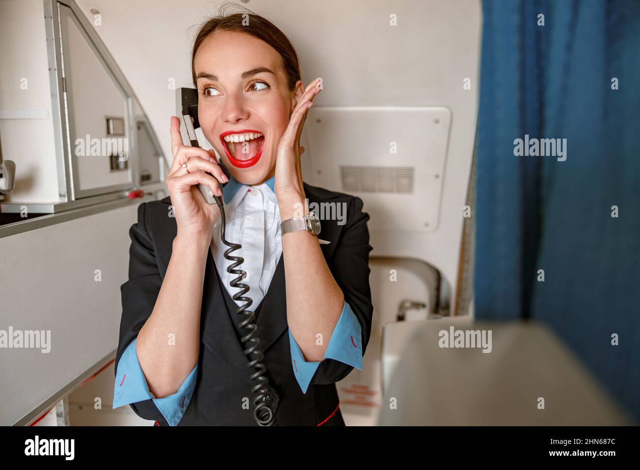 Cheerful flight attendant talking on telephone in airplane Stock Photo ...