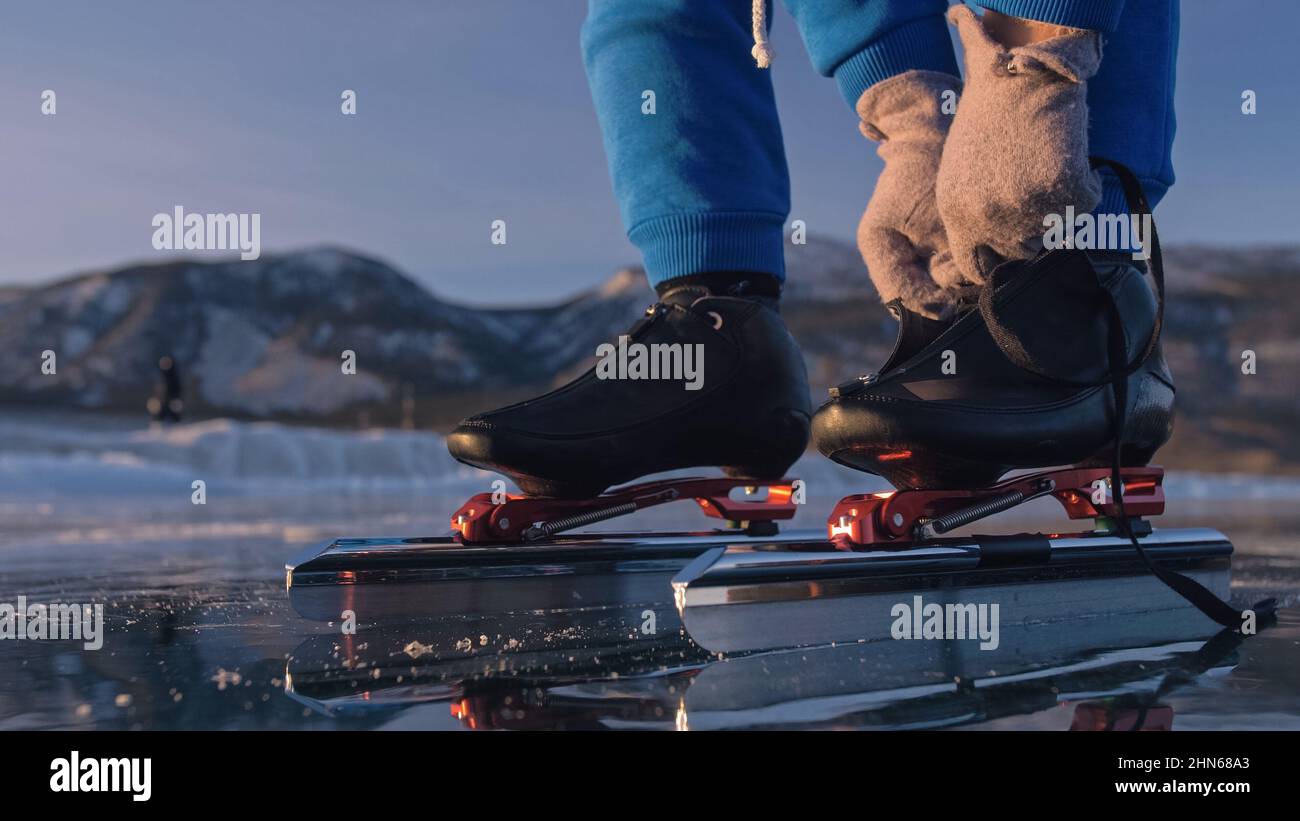 The child train on ice speed skating. Athlete puts on skates. The girl ...