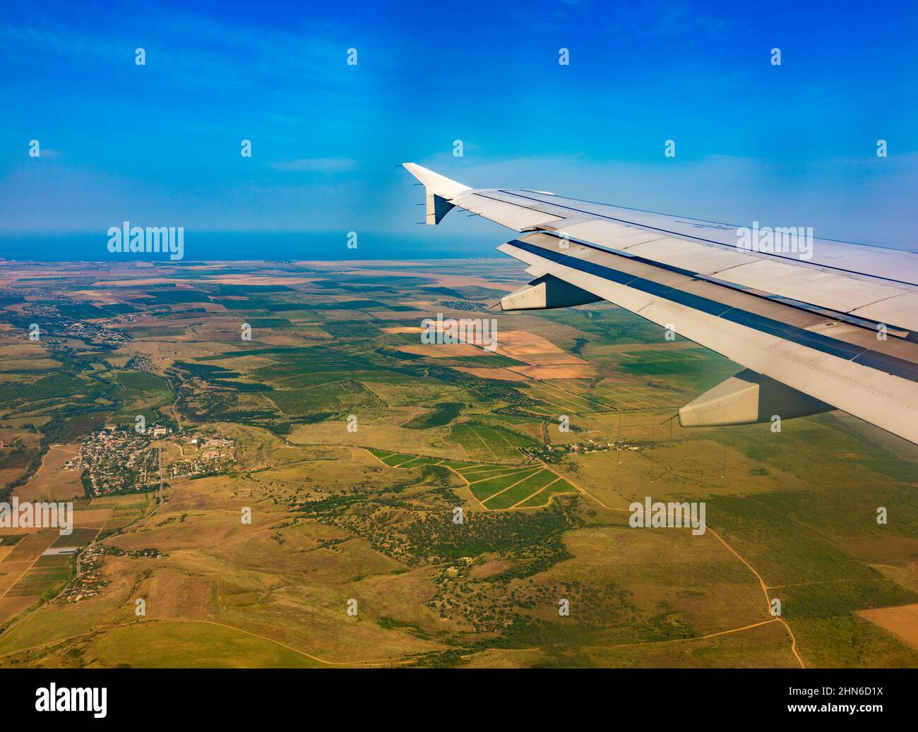 View of airplane wing, blue skies and green land during landing ...