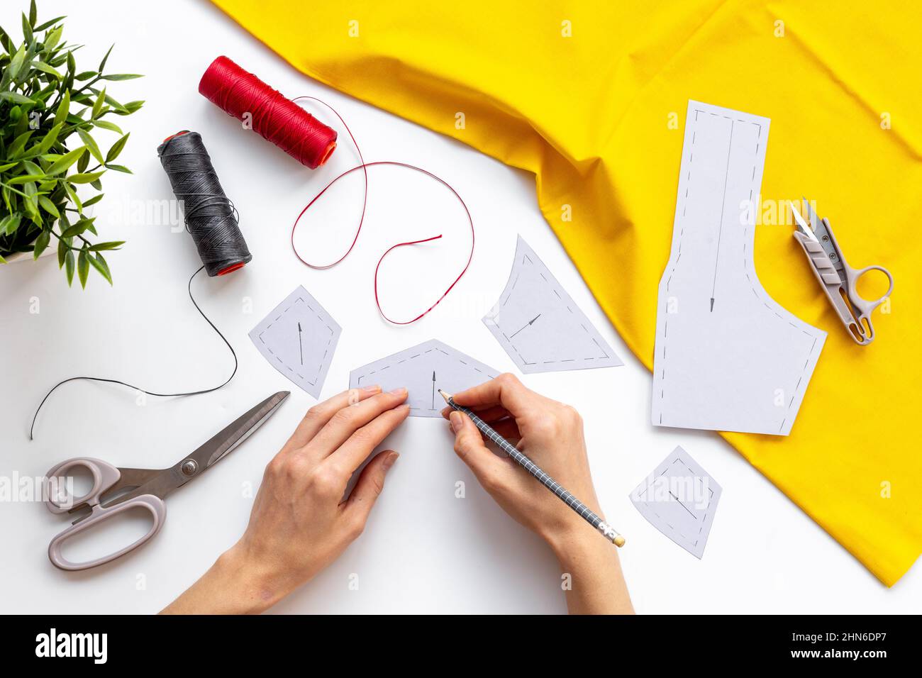 Workplace of seamstress. Hands doing sewing patterns with fabric Stock ...