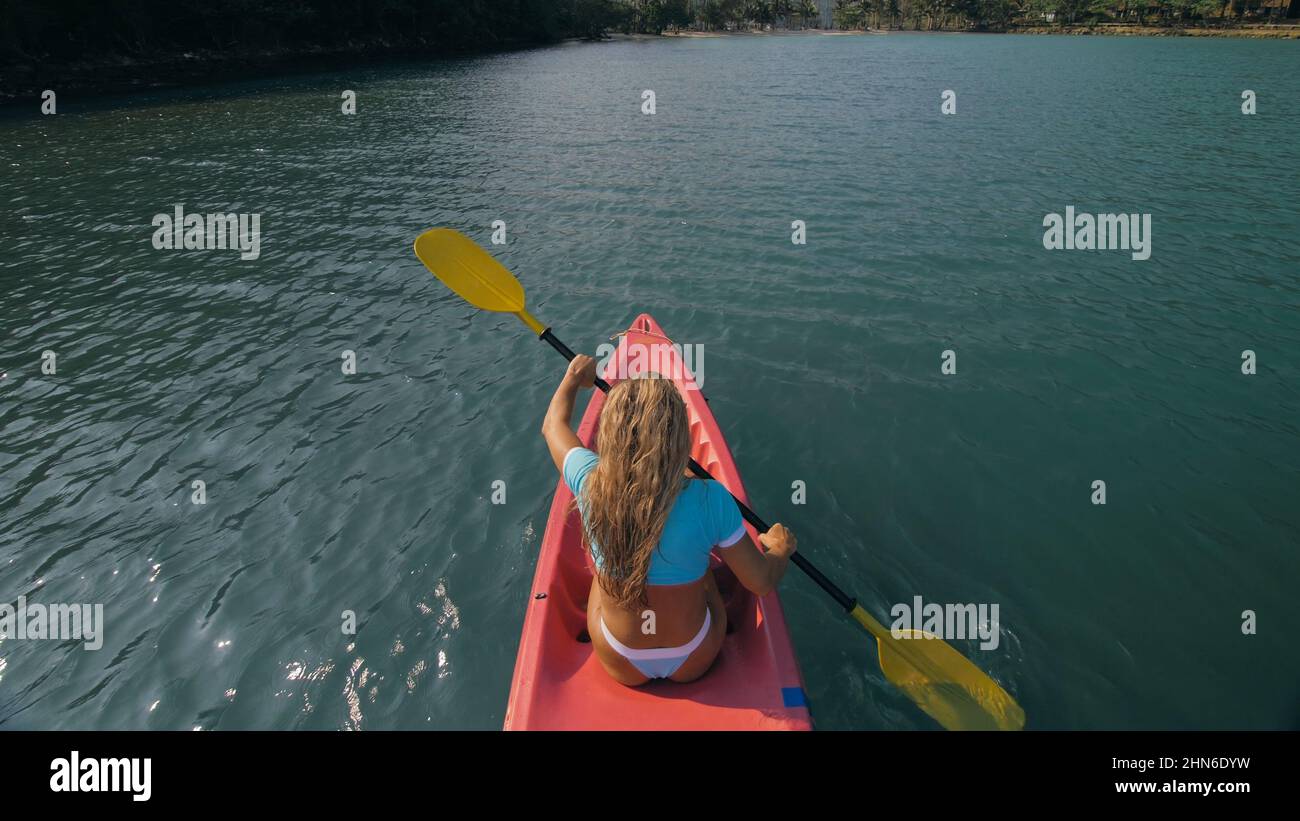 Seductive blonde woman in blue swimsuit sails on pink plastic kayak ...