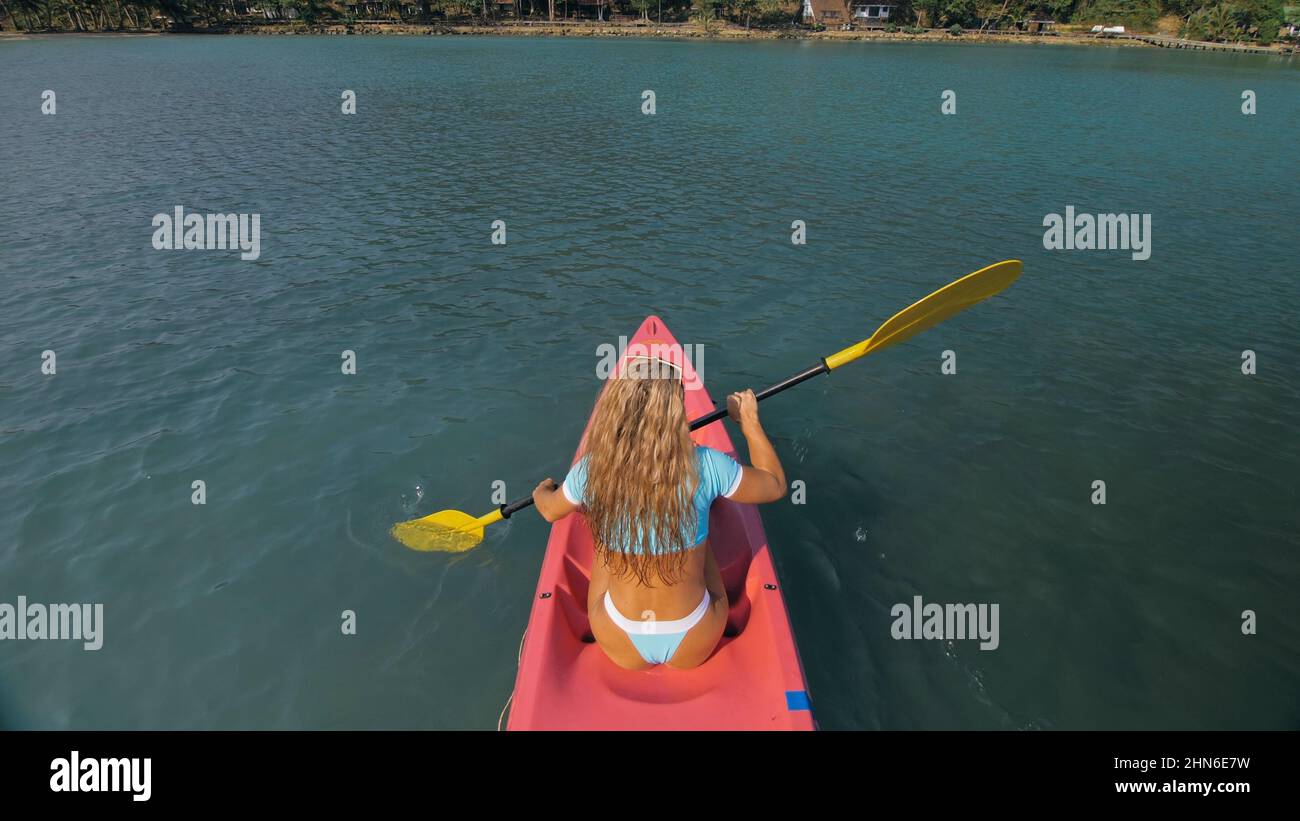 Seductive blonde woman in blue swimsuit sails on pink plastic kayak ...