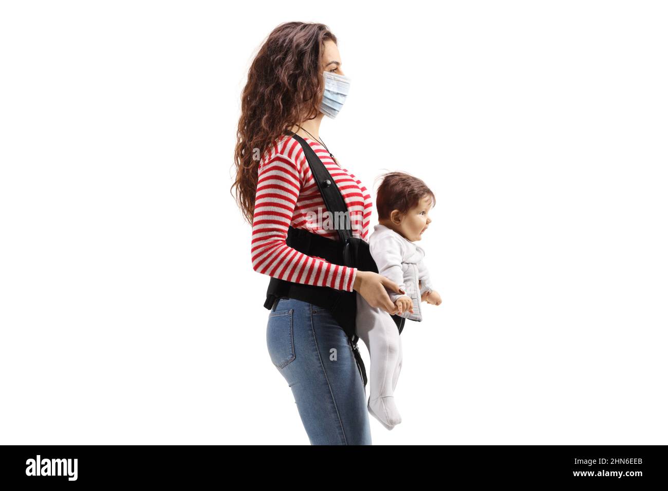 Mother with a baby in a carrier wearing a protective medical mask ...