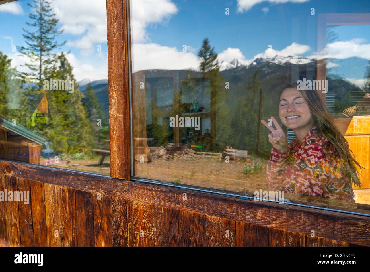 Female showing the peace sign through a mountain cabin window Stock ...