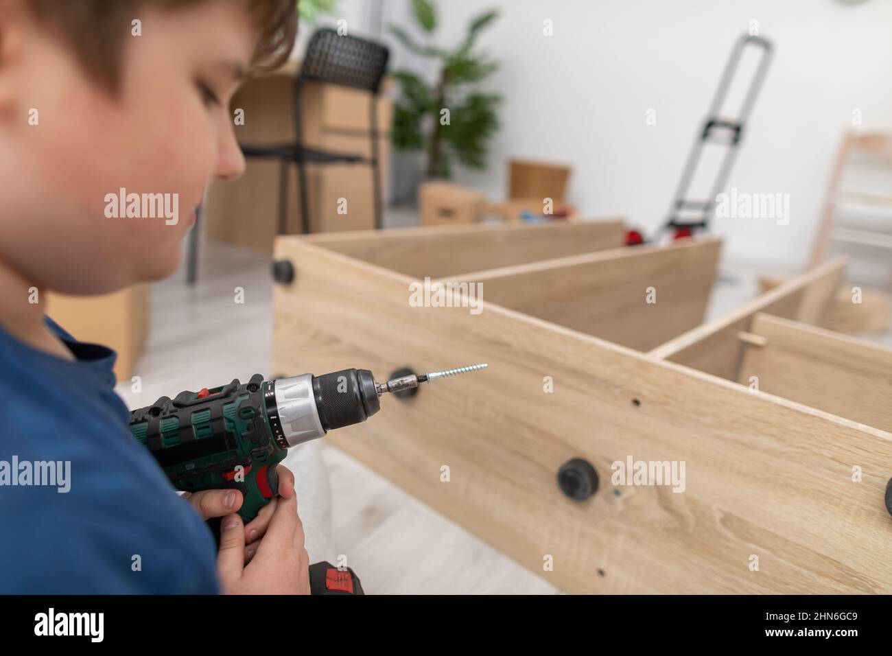 A young boy holds a cordless screwdriver in his hand and wonders Stock ...