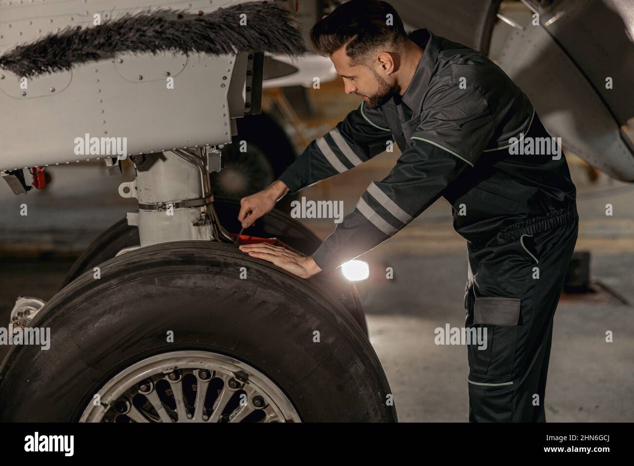 Male aviation mechanic repairing aircraft wheel in hangar Stock Photo ...