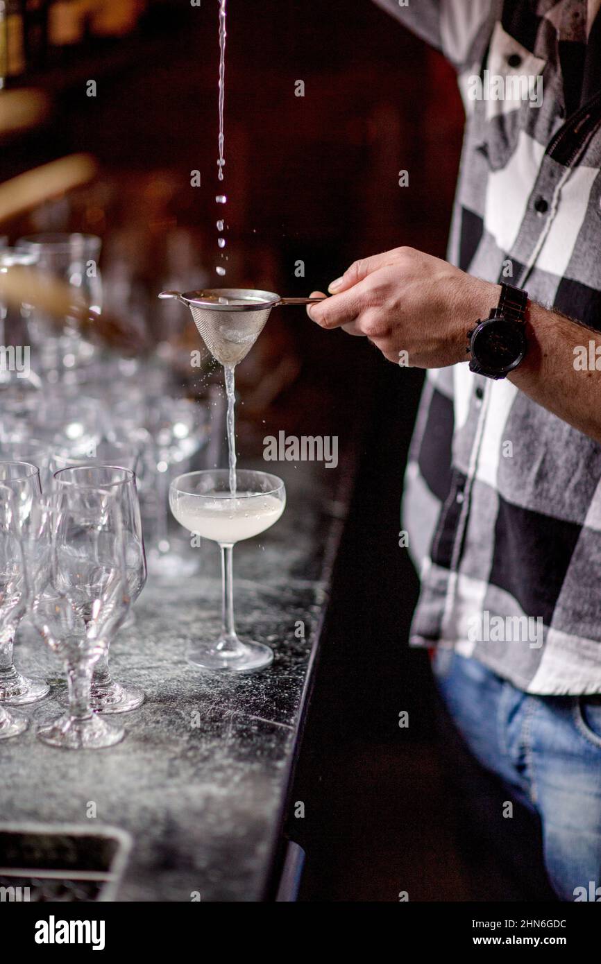 Male bartender straining lemon martini from up high Stock Photo - Alamy