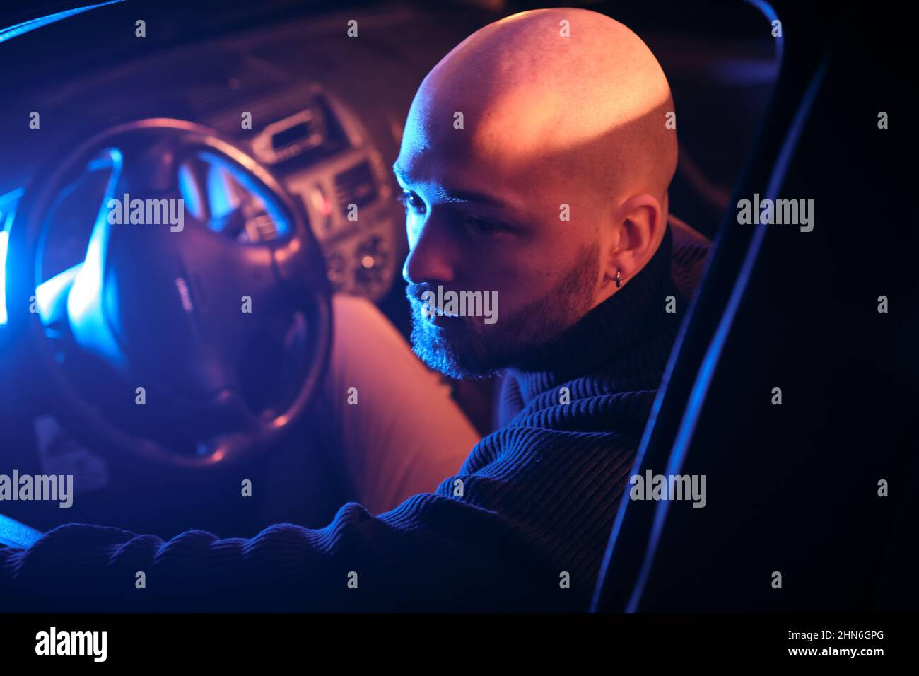 Portrait of a bald young man driving illuminated by a blue light Stock ...