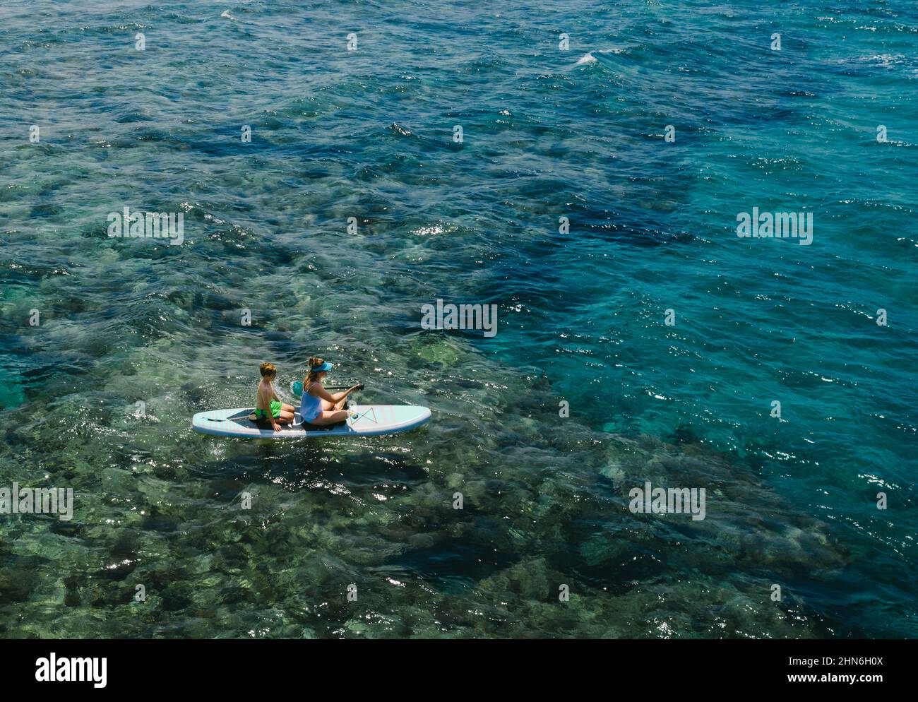 Mom and son stand up paddle boarding over ocean coral reefs Stock Photo ...