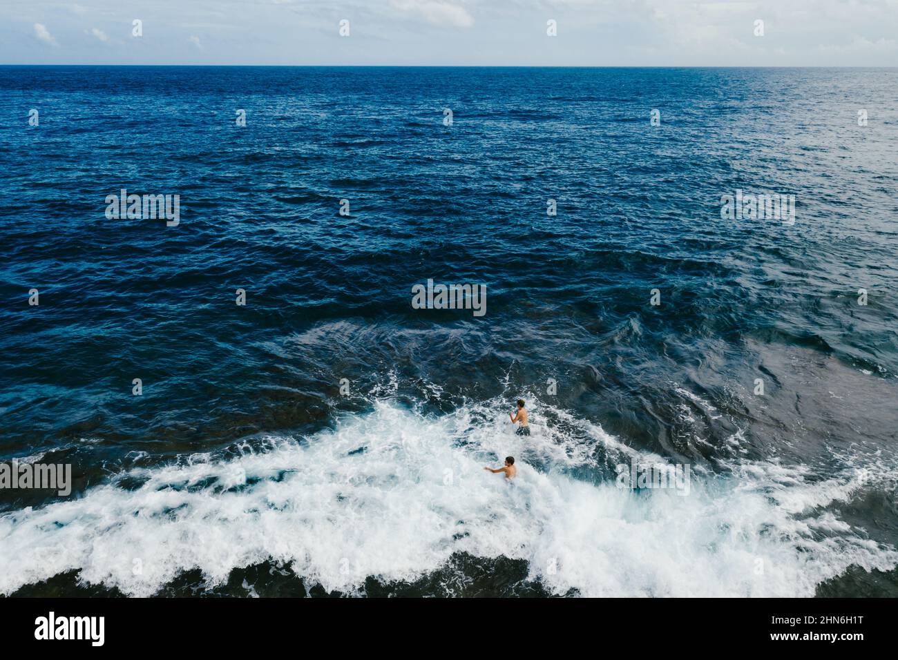 Two boys playing in the waves on the edge of the blue ocean Stock Photo ...