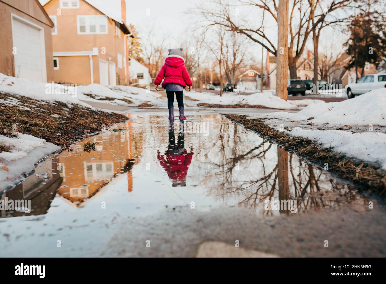 Wide shot of Young girl standing in puddle looking at reflection Stock ...