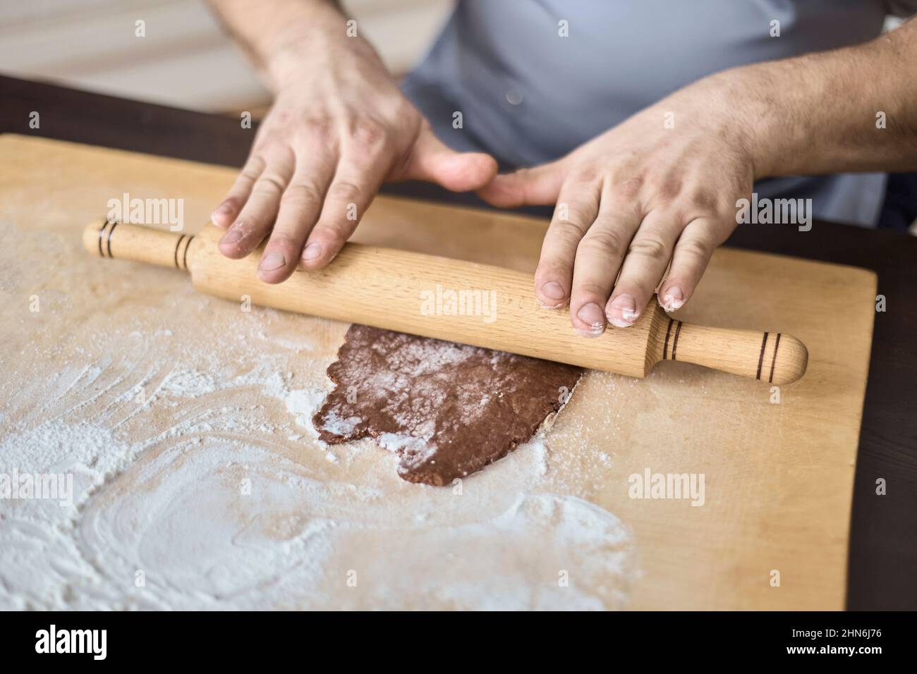 A man's hands roll out the chocolate dough with a rolling pin Stock ...