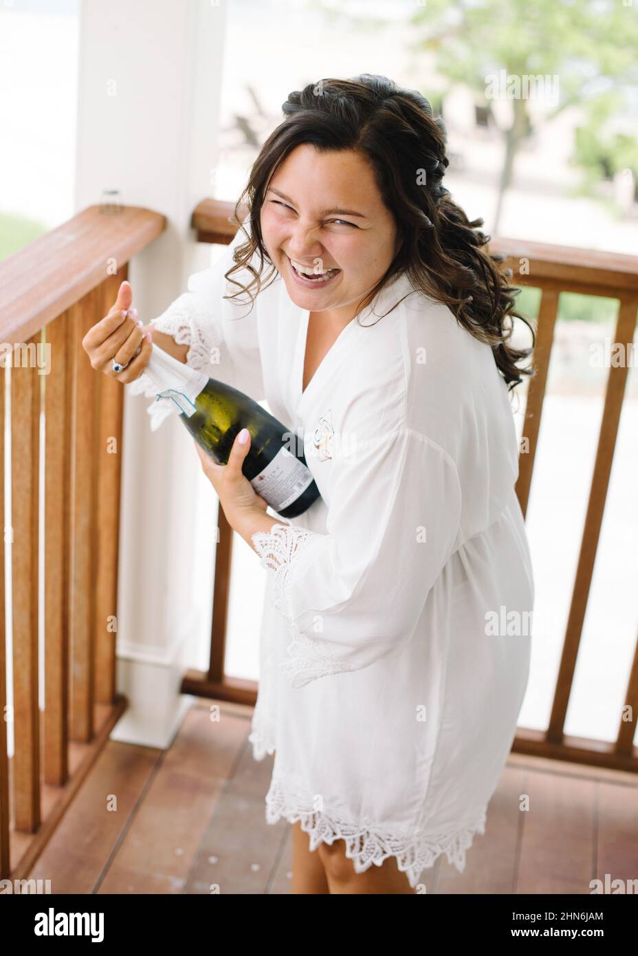 Excited bride opening a bottle of champagne on her wedding day Stock ...