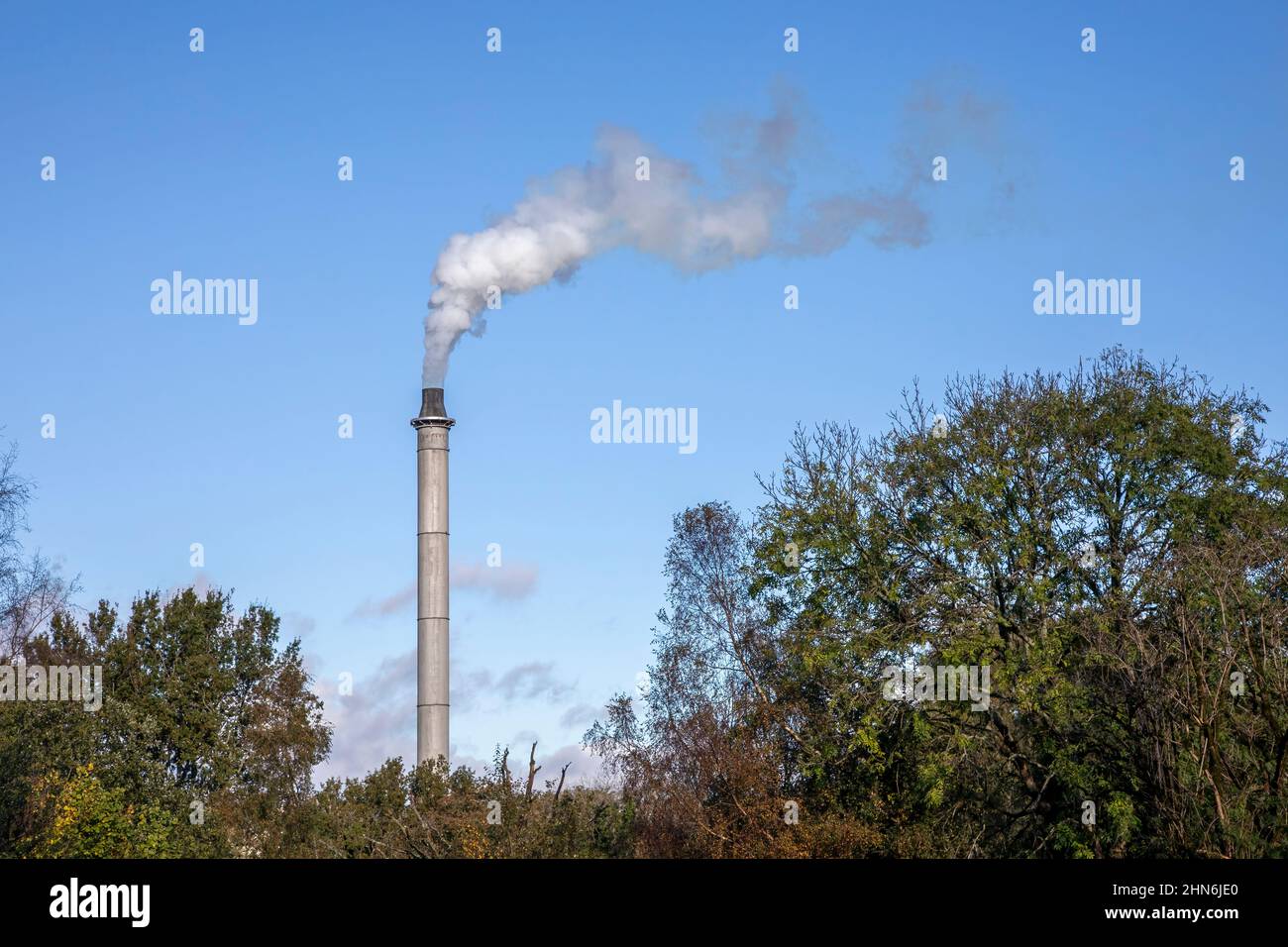 A landscape of an industrial factory chimney, smoking against a blue ...