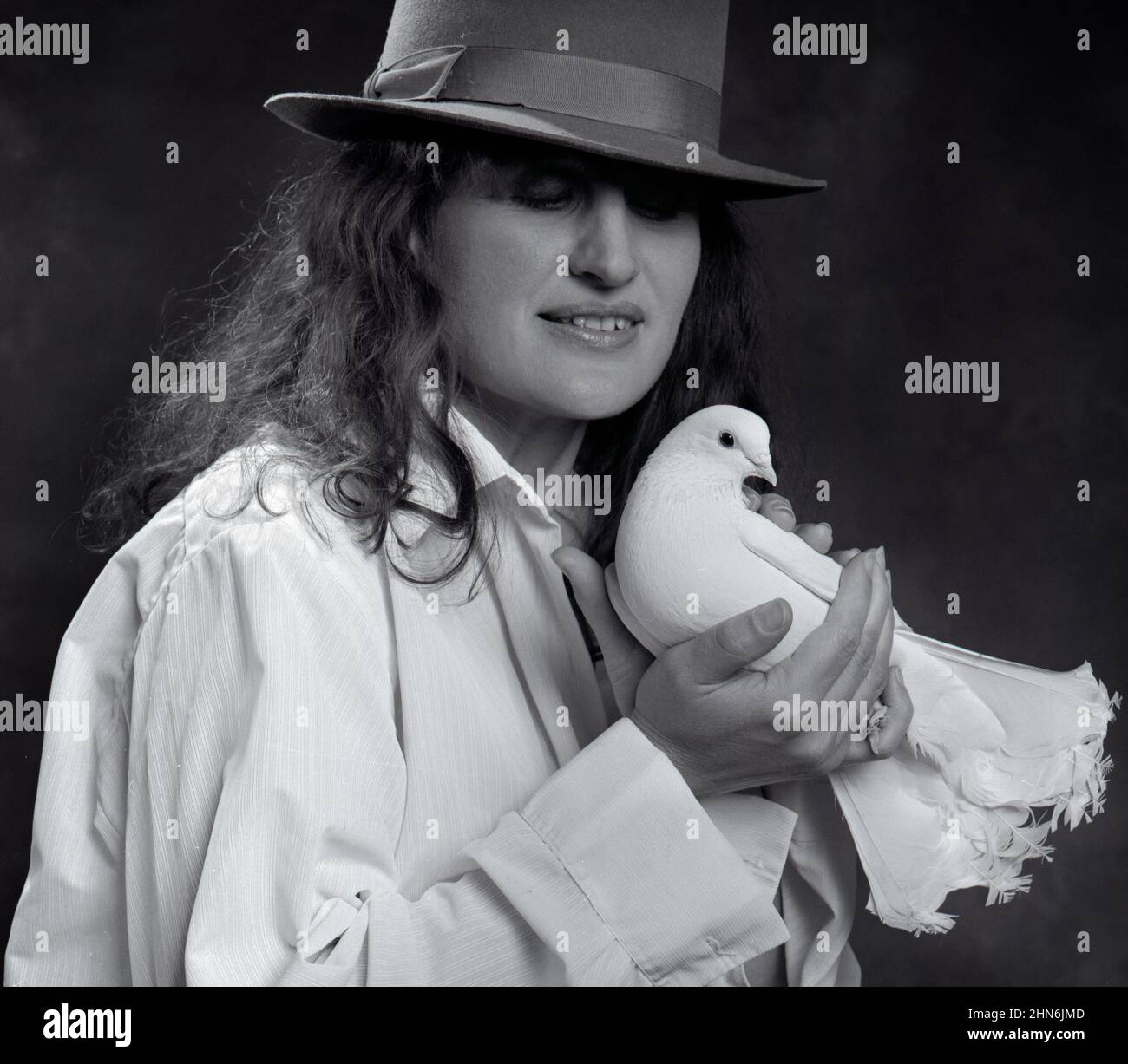 Cute long hair woman in man hat hold a beautiful white dove in her ...