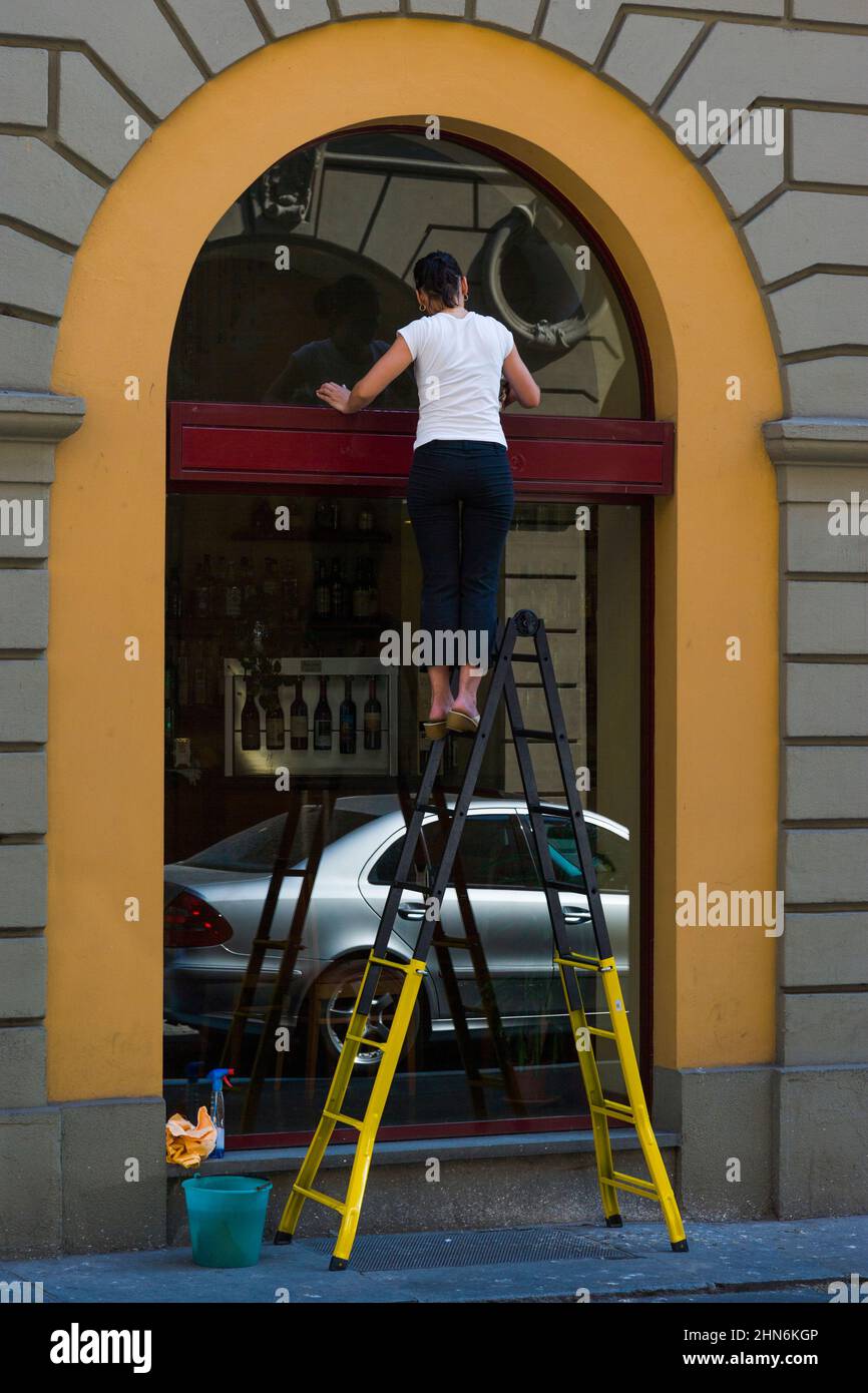 Woman on a ladder cleaning store window, Alba, Italy Stock Photo - Alamy