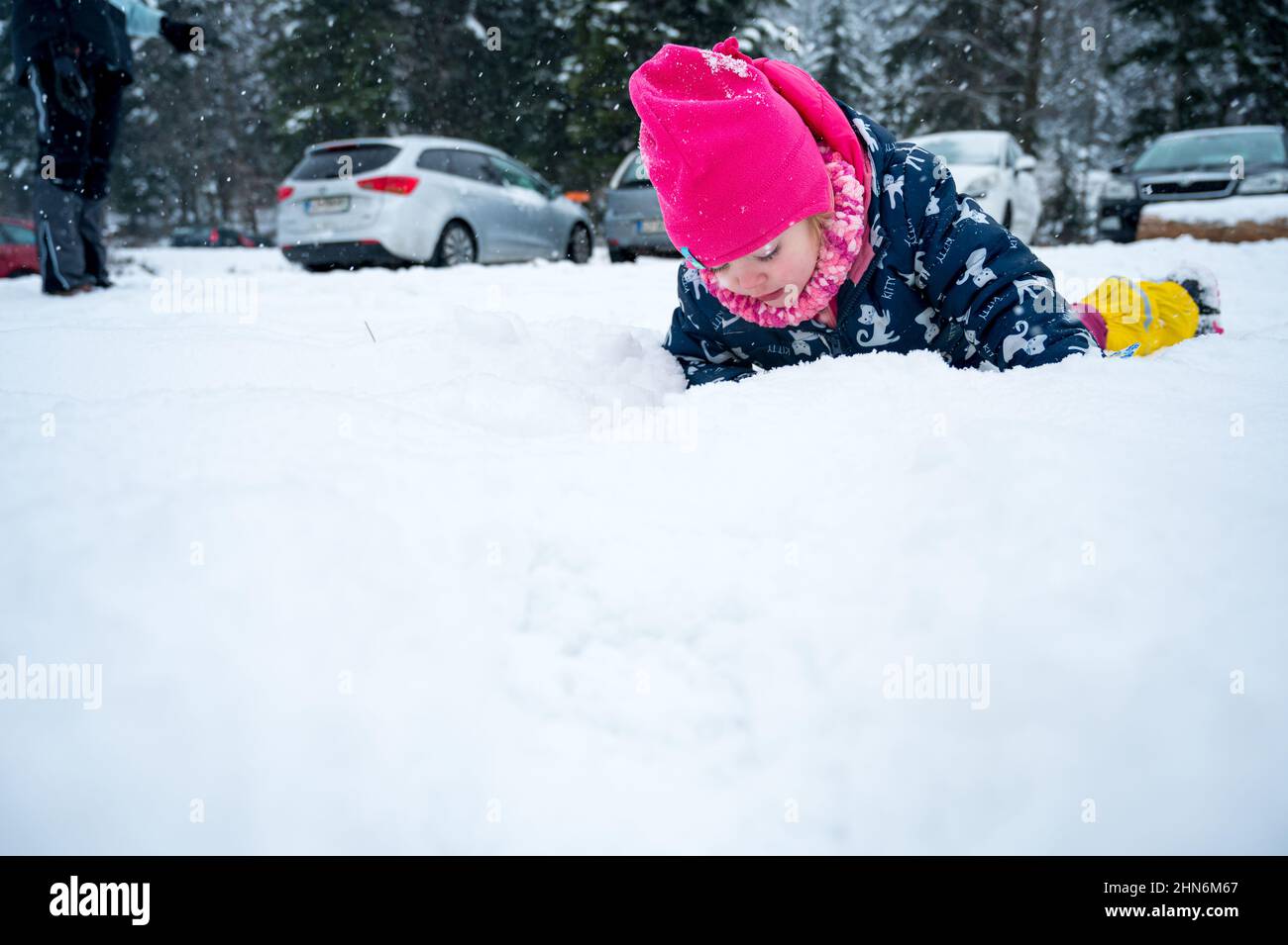 Cute girl examinating snow up close while lying on the ground Stock ...