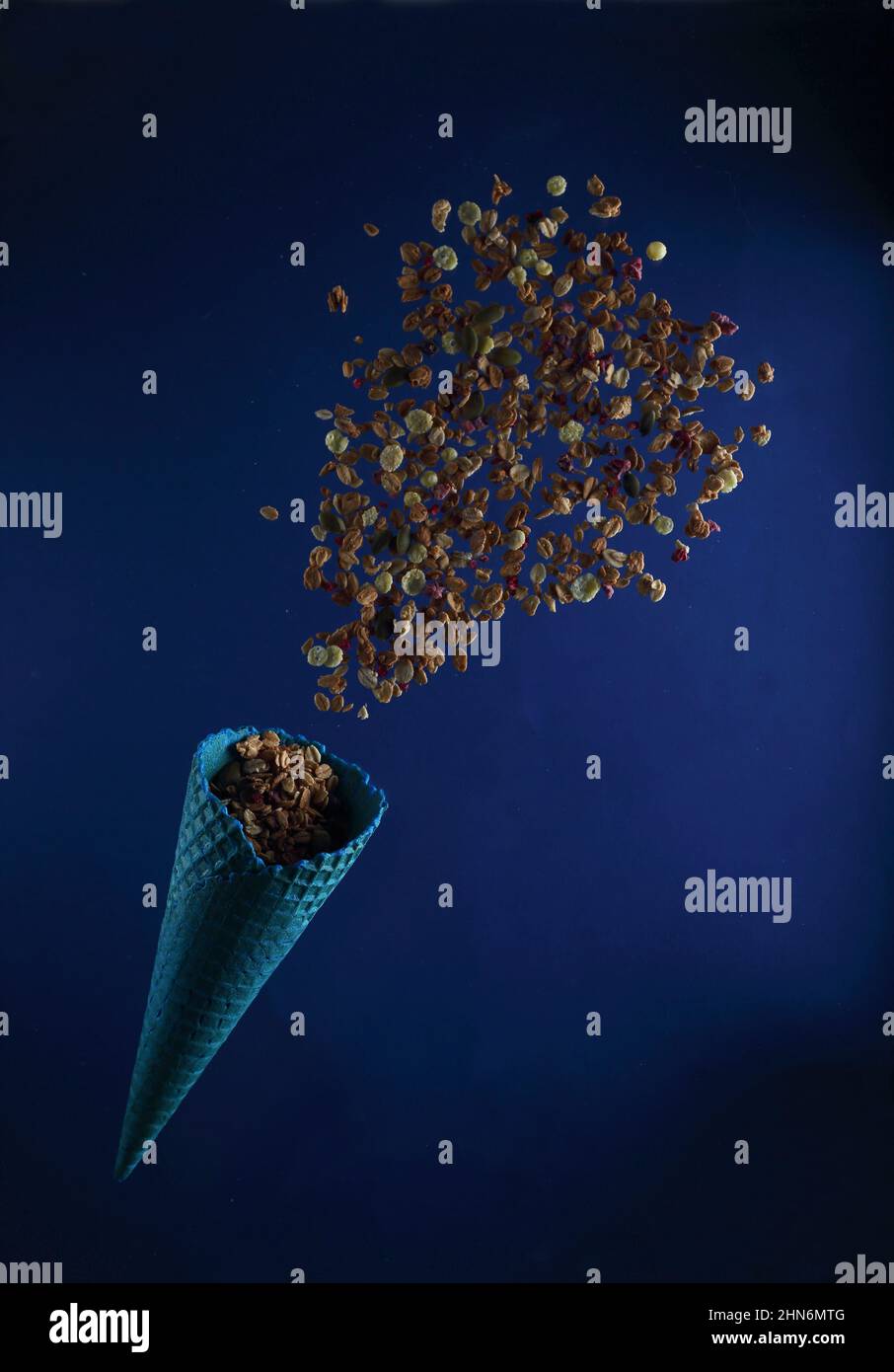 granola pouring from blue waffle cone against blue background. Image ...
