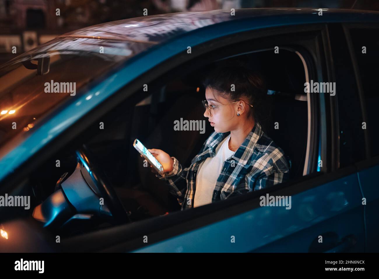 Lost female driver using mobile phone while driving at night Stock ...