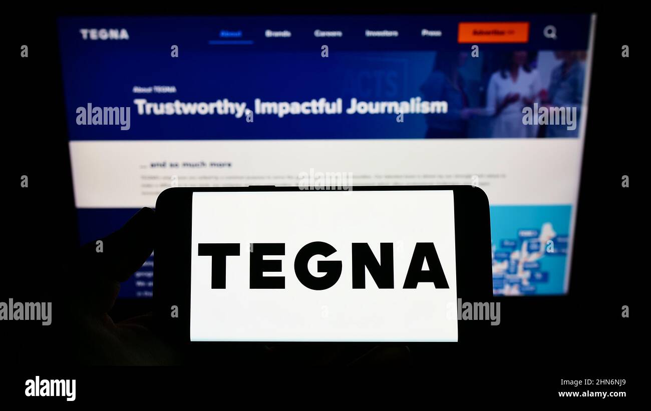 Person holding mobile phone with logo of American broadcasting company ...