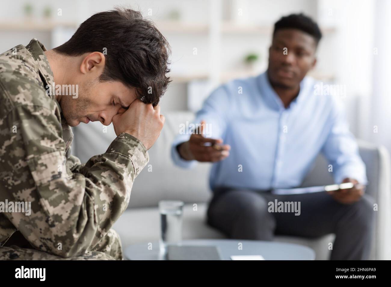 Distressed young man soldier attending therapy session with ...