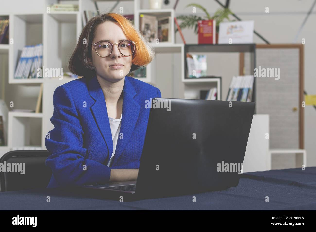 Secretary girl in blue business suit and multi-colored hair sits table ...