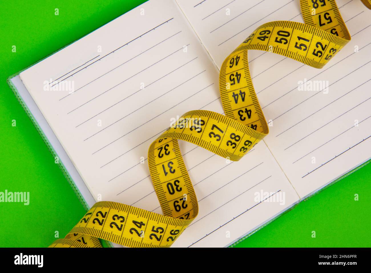 Yellow tape measure with paper note on green background Stock Photo - Alamy