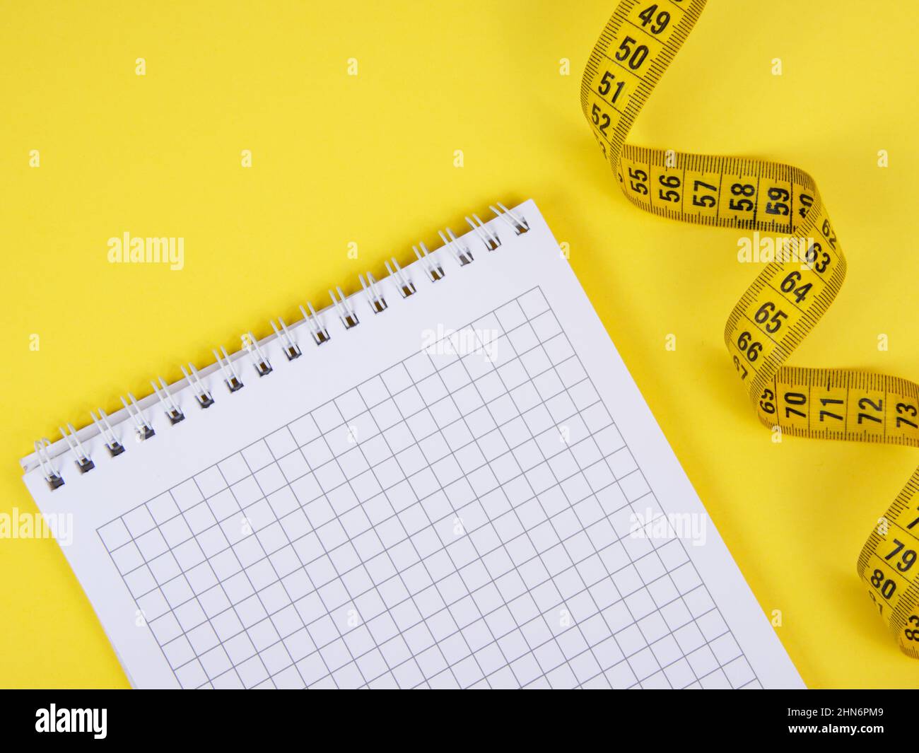 Yellow tape measure centimetric with paper note on yellow background ...
