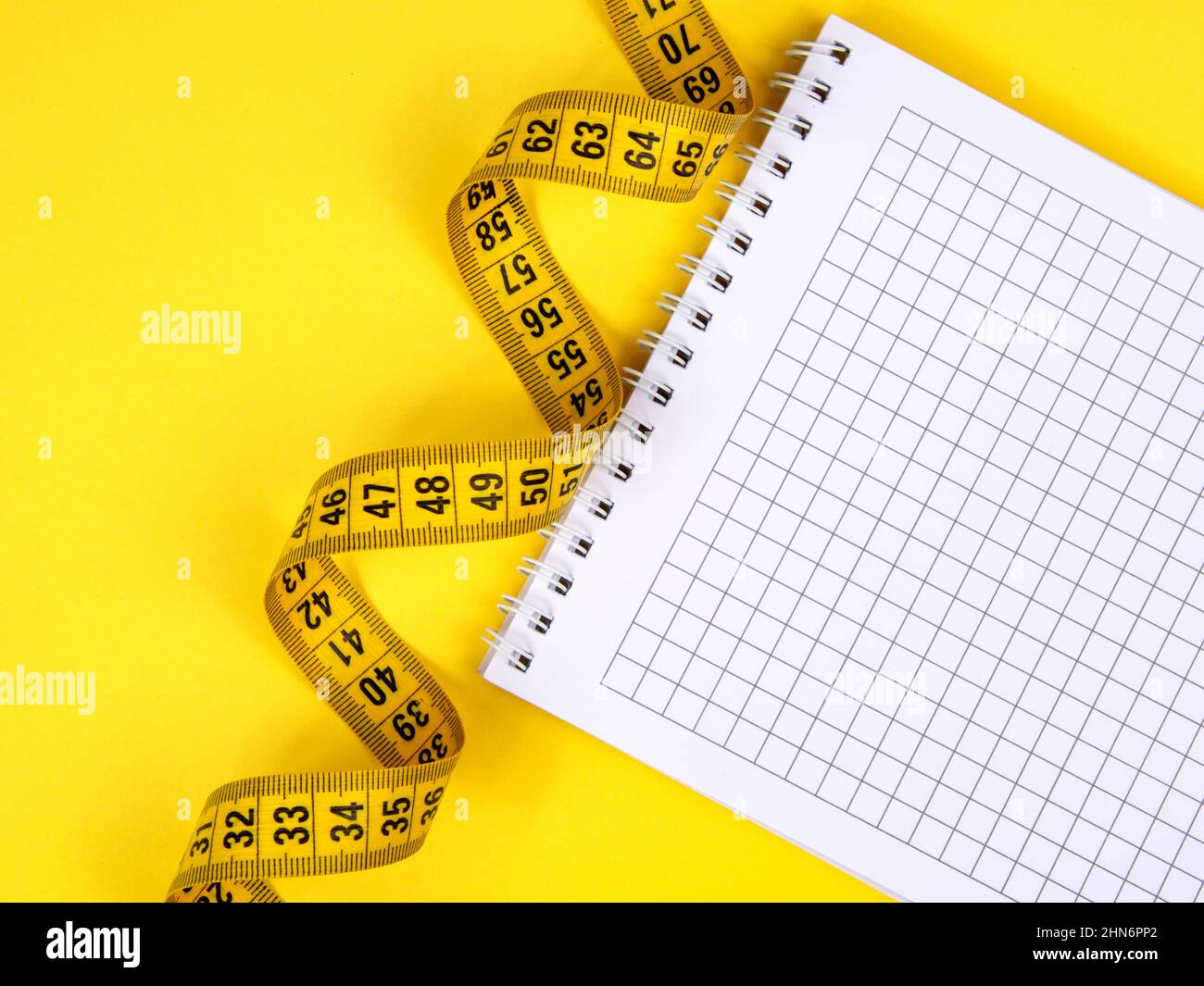 Yellow tape measure centimetric with paper note on yellow background ...