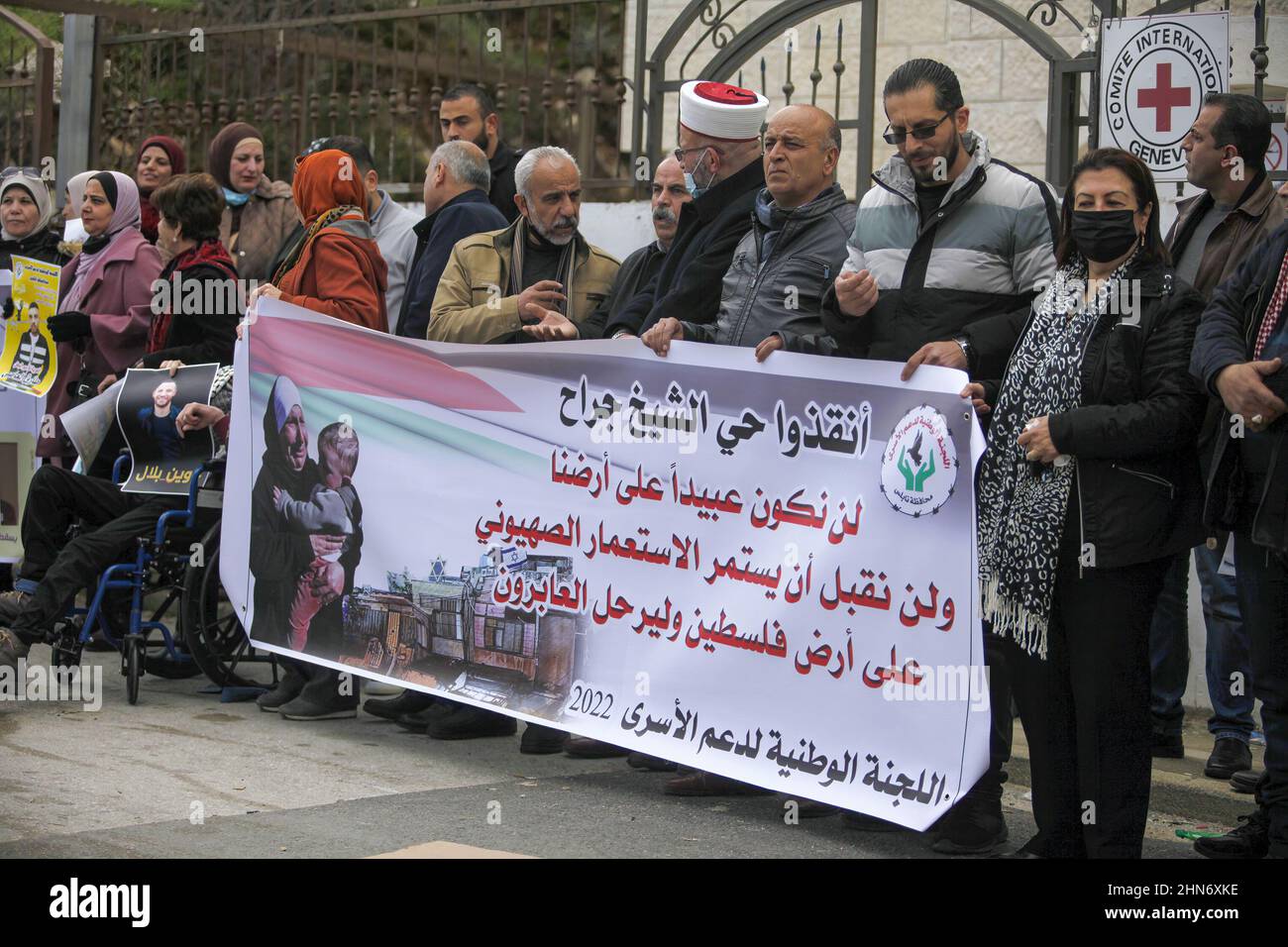A Palestinian man in a wheel chair holds a placard next to a banner ...